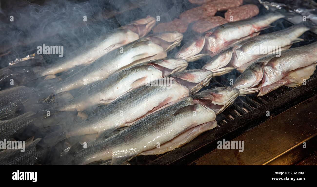 Grilled sea bass fish closeup. In process. European sea-bass, chef is ...