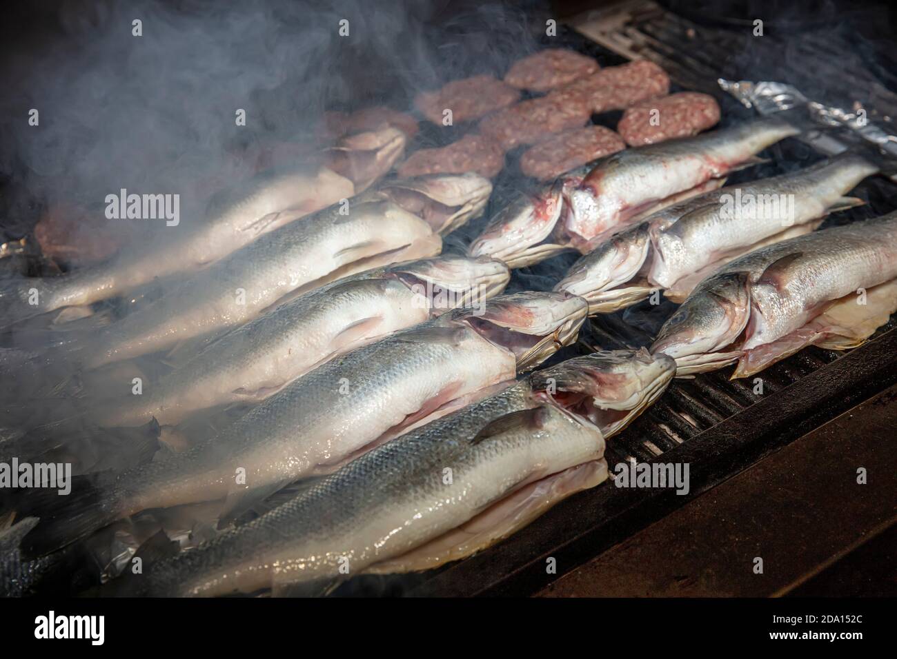 Grilled sea bass fish closeup. In process. European sea-bass, chef is ...