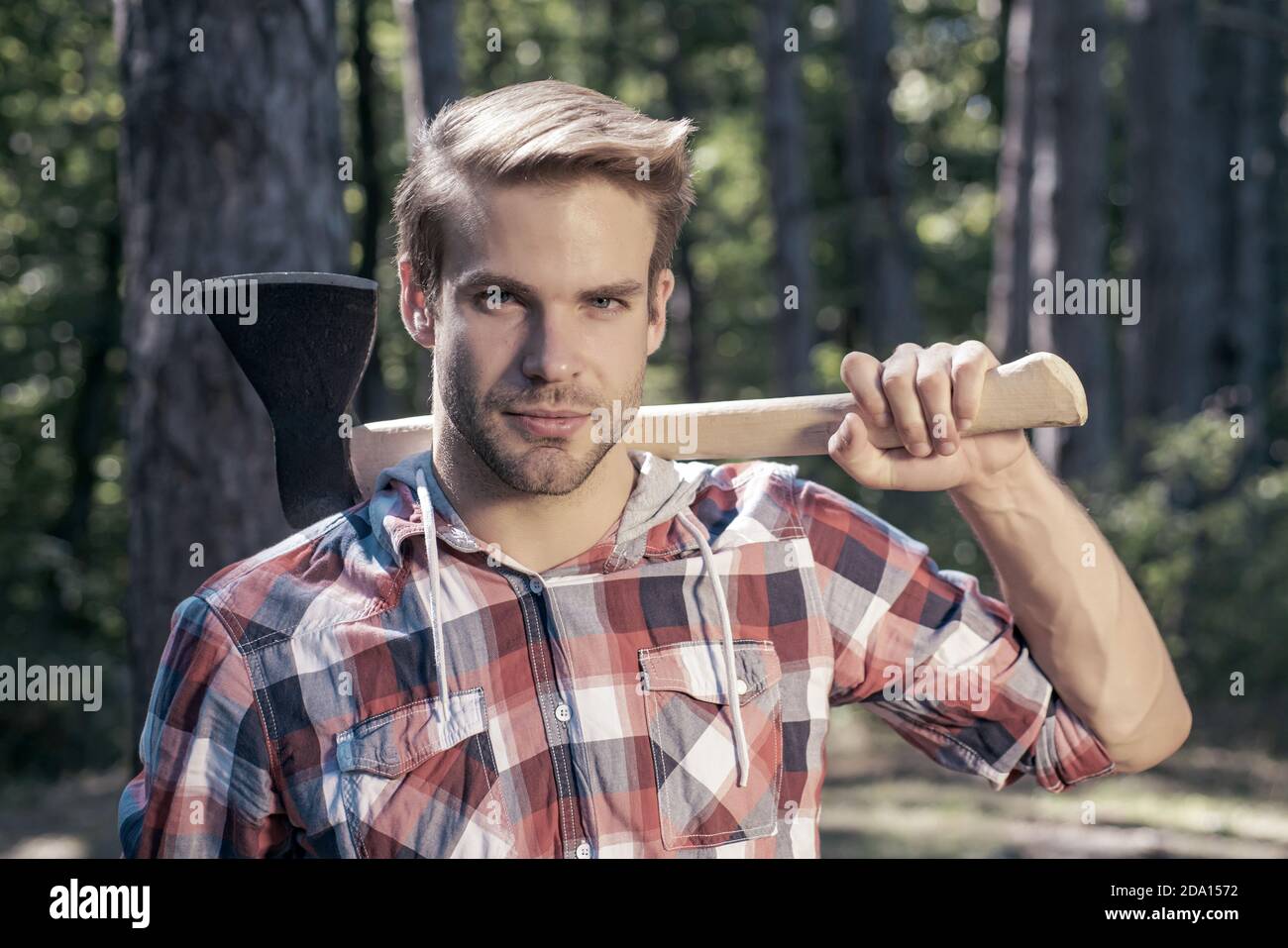 Lumberjack carries axe on shoulder. Deforestation. Handsome man with ...