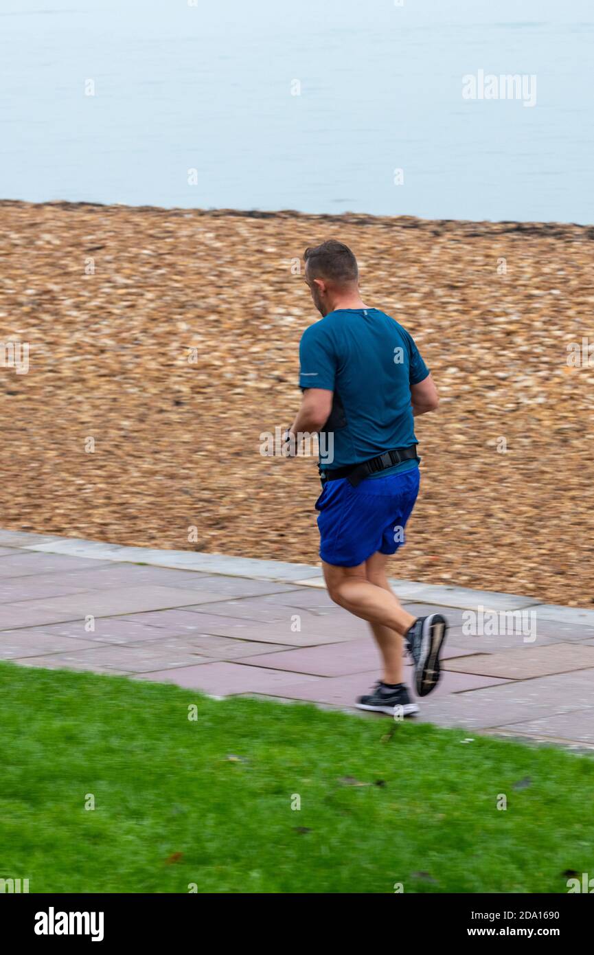 middle-aged man running along a path at the beach or seaside to keep ...