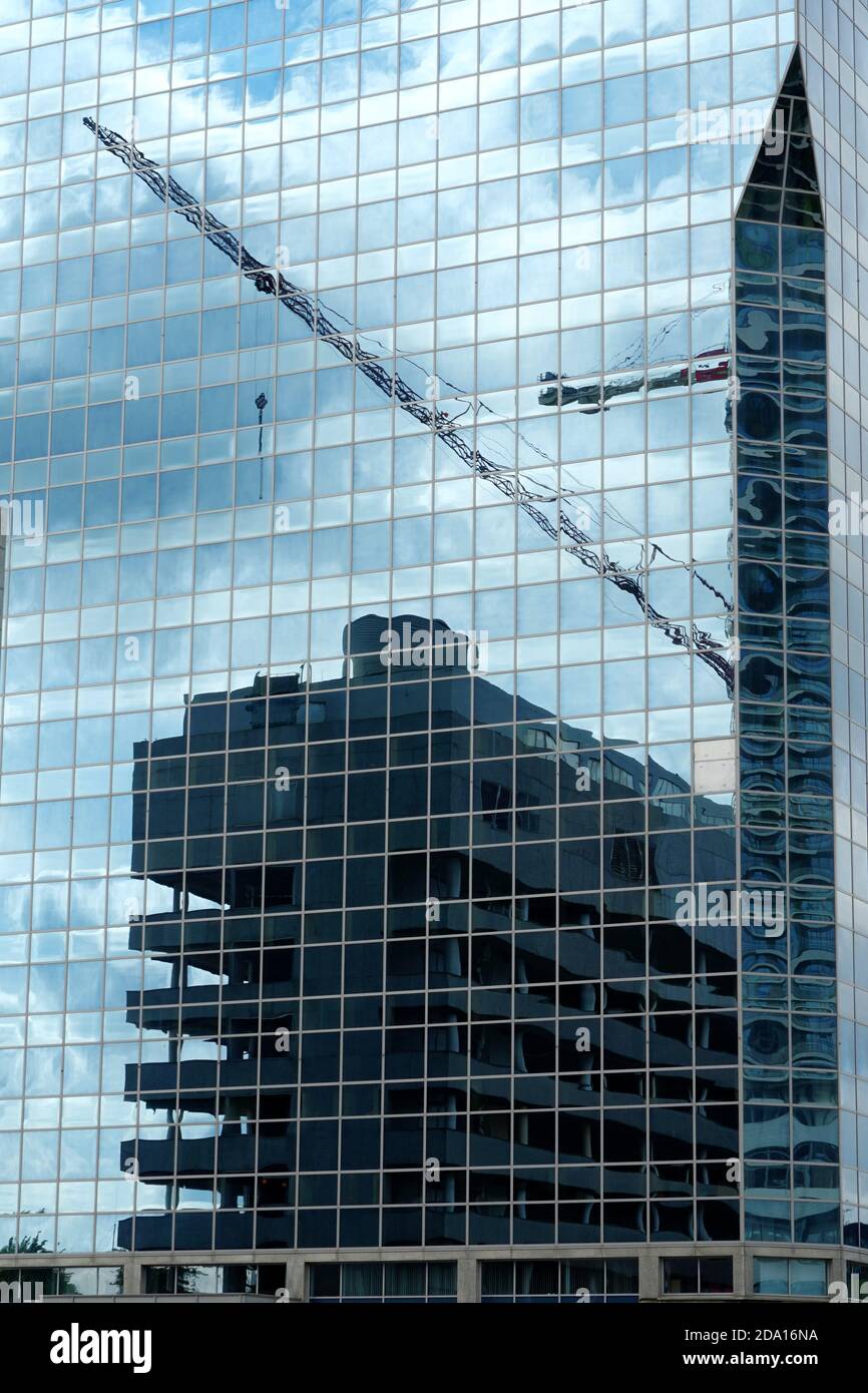 A facade of a modern corporate building reflecting another building in ...