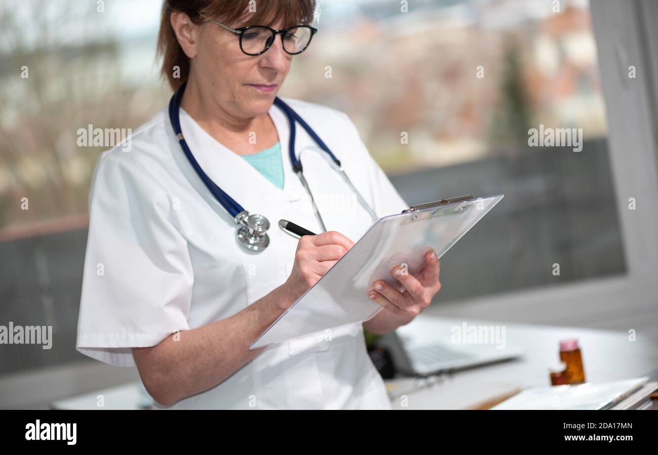 Female doctor taking notes on clipboard in medical office Stock Photo ...