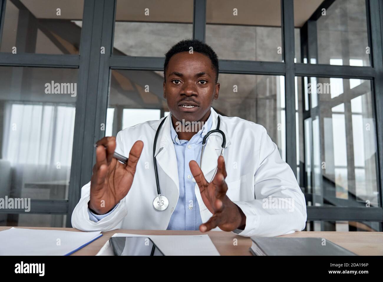 Black male doctor talking to web cam during virtual telemedicine advice ...