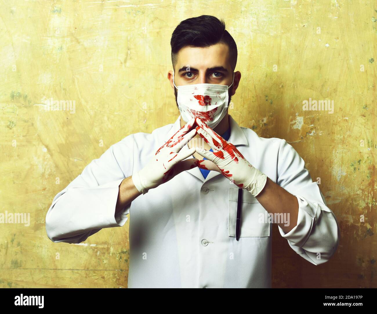 Surgeon with stylish haircut in mask stained with blood holds his hands ...