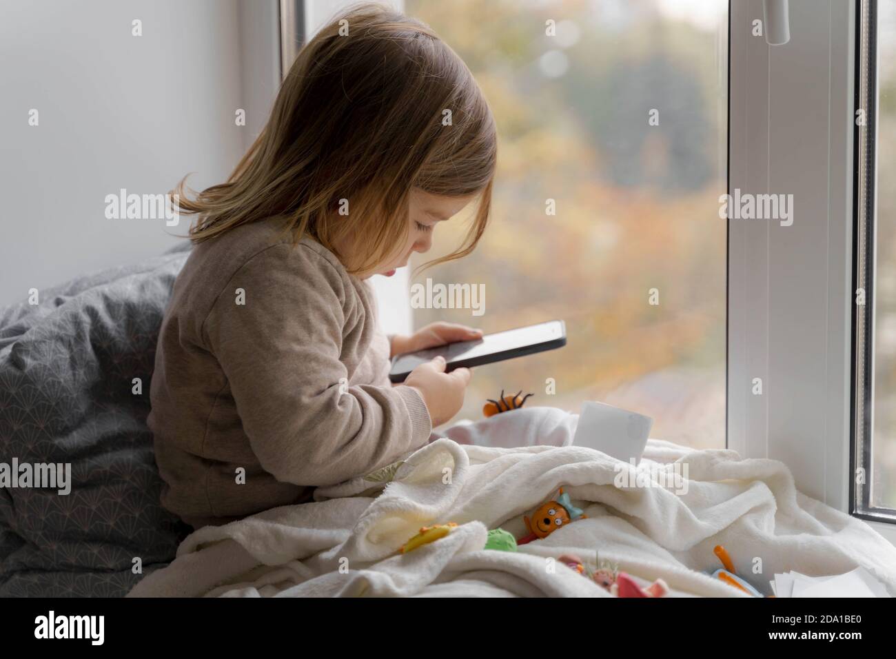 toddler child using phone at home, taking photos and playing games ...