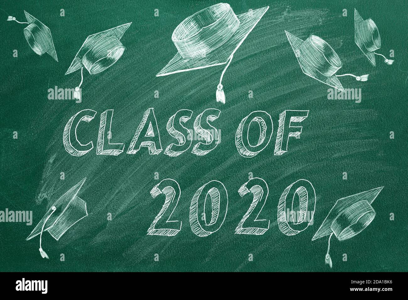 Hand drawing "Class of 2020" and graduation caps on green chalkboard ...