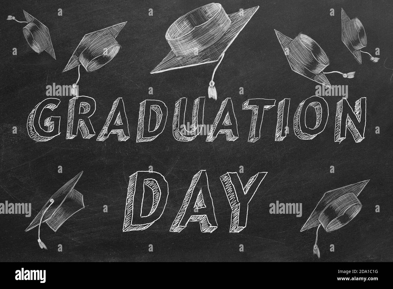 Hand drawing text "Graduation day" and graduation caps on blackboard ...
