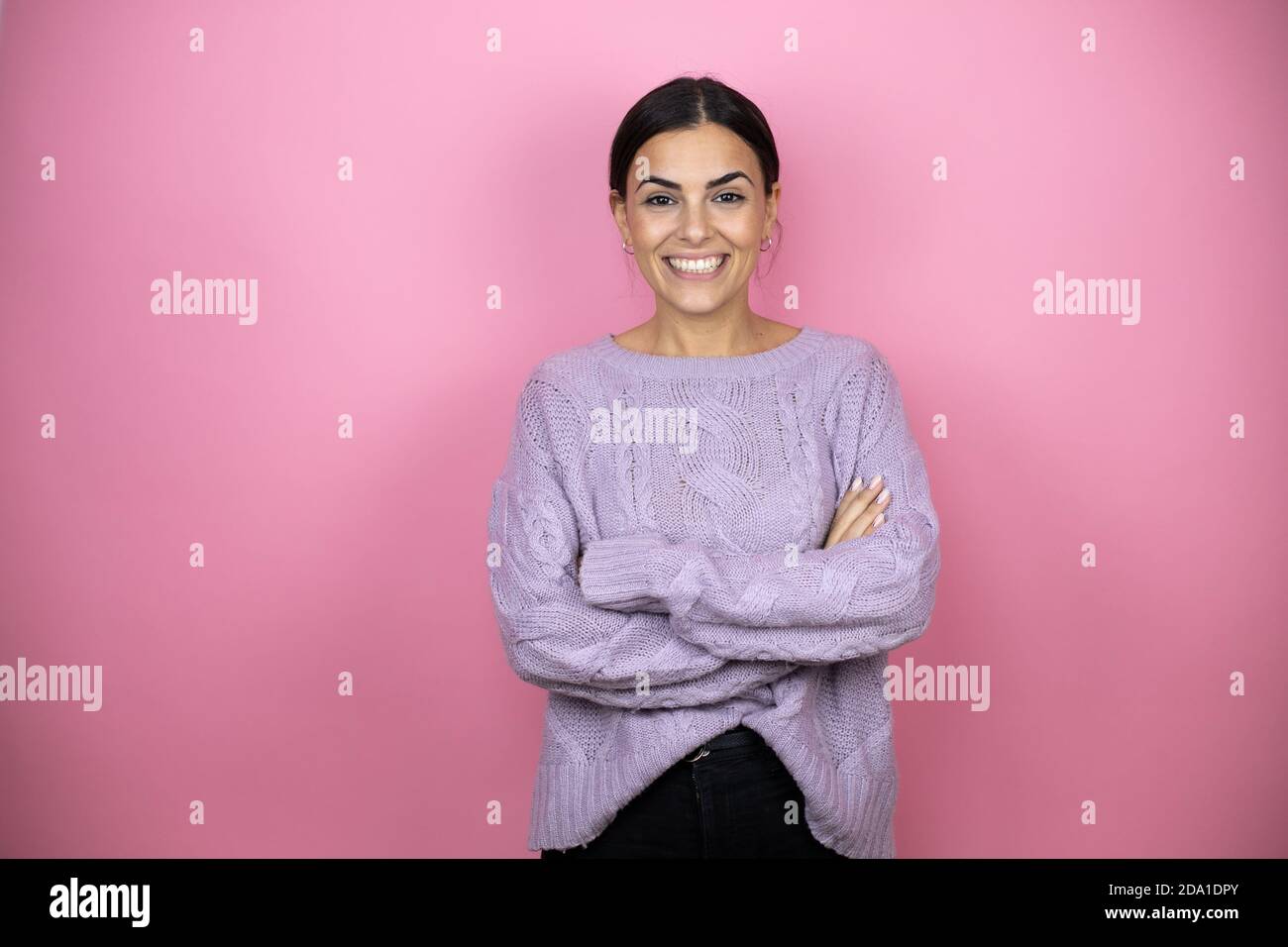 Beautiful woman wearing a casual violet sweater over pink background ...