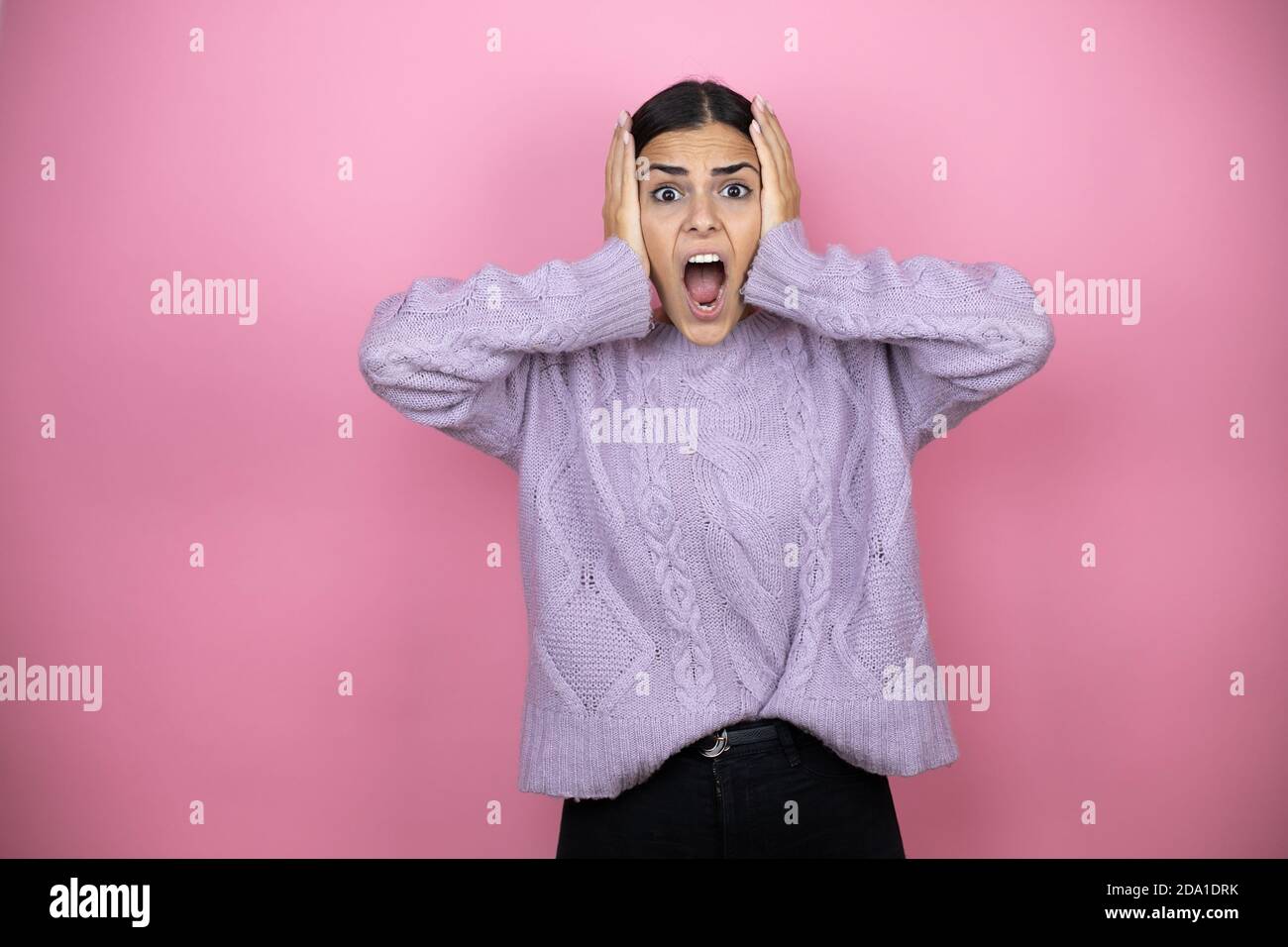 Beautiful woman wearing a casual violet sweater over pink background ...
