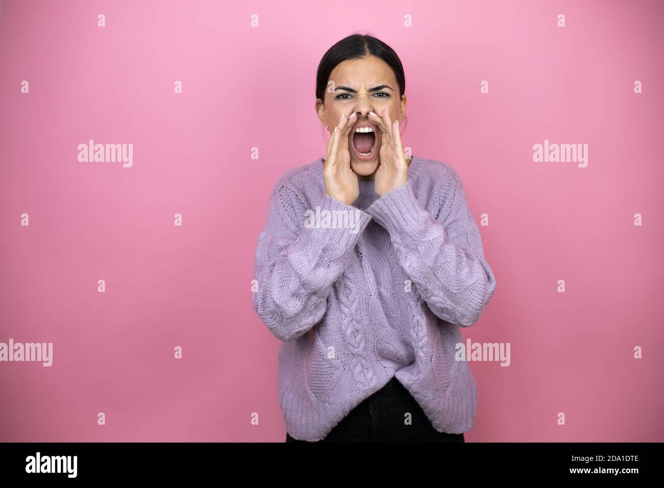 Beautiful woman wearing a casual violet sweater over pink background ...