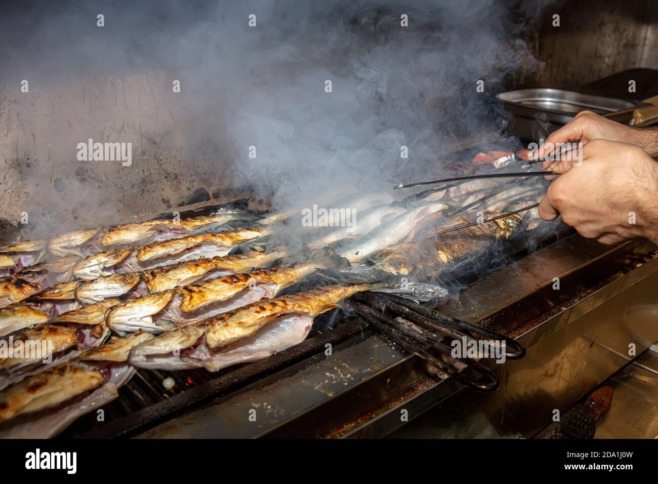 Grilled sea bass fish closeup. In process. European sea-bass, chef is ...