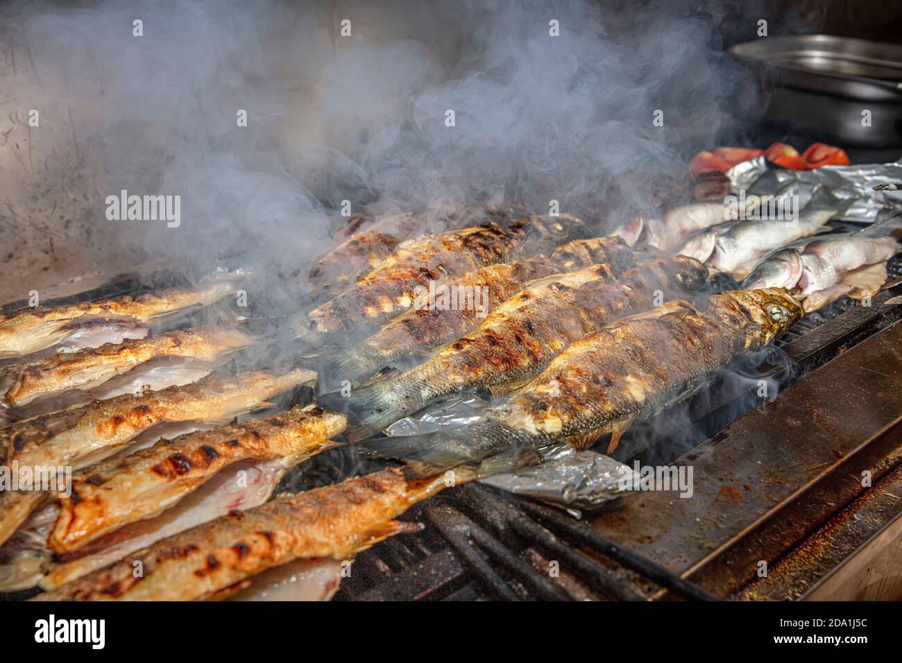 Grilled sea bass fish closeup. In process. European sea-bass, chef is ...
