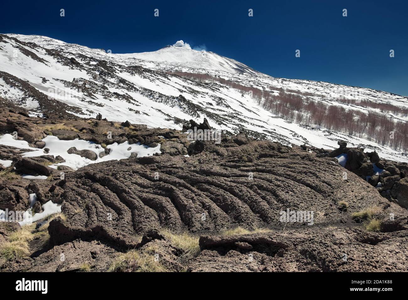 cooled lava flow ropy surface, on background winter Etna Volcano ...