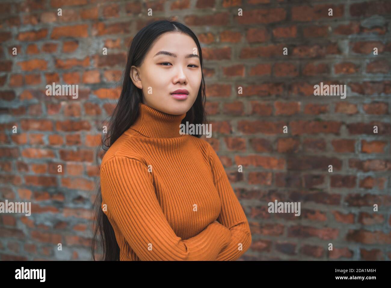 Asian woman against brick wall Stock Photo - Alamy