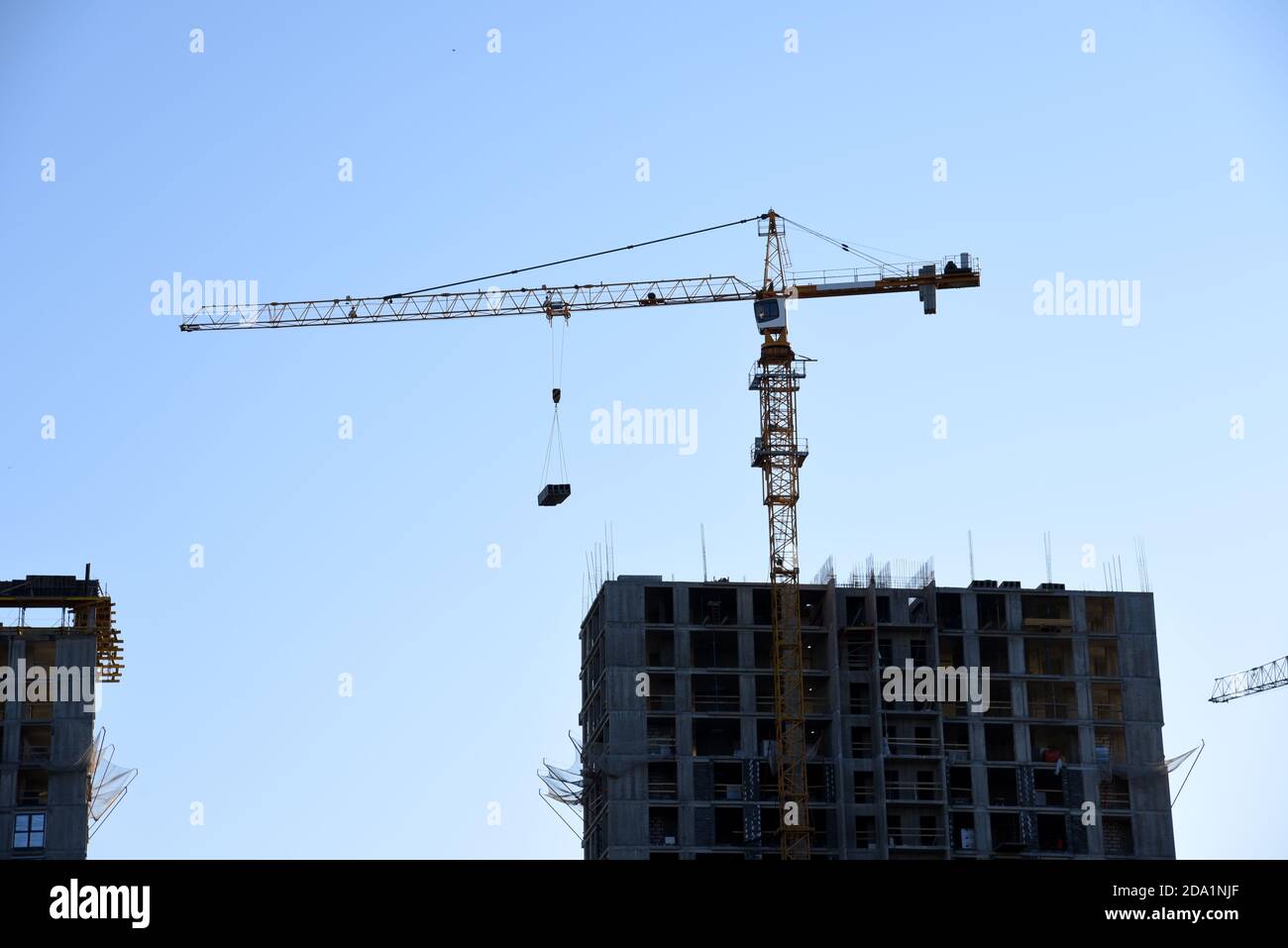 Tower crane working at construction site against blue sky background ...