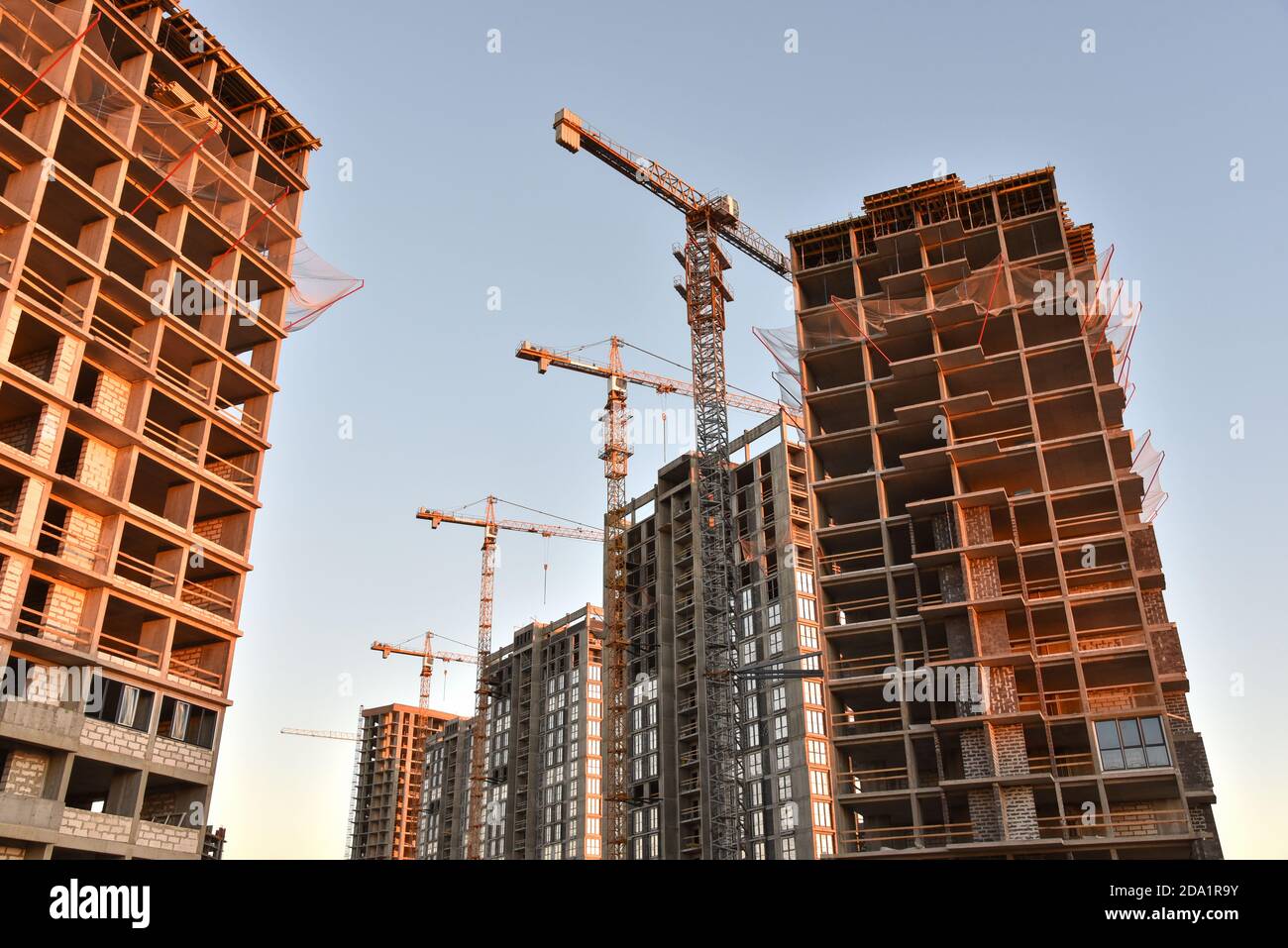 Tower cranes against the blue sky during sunset. Construction of a new ...