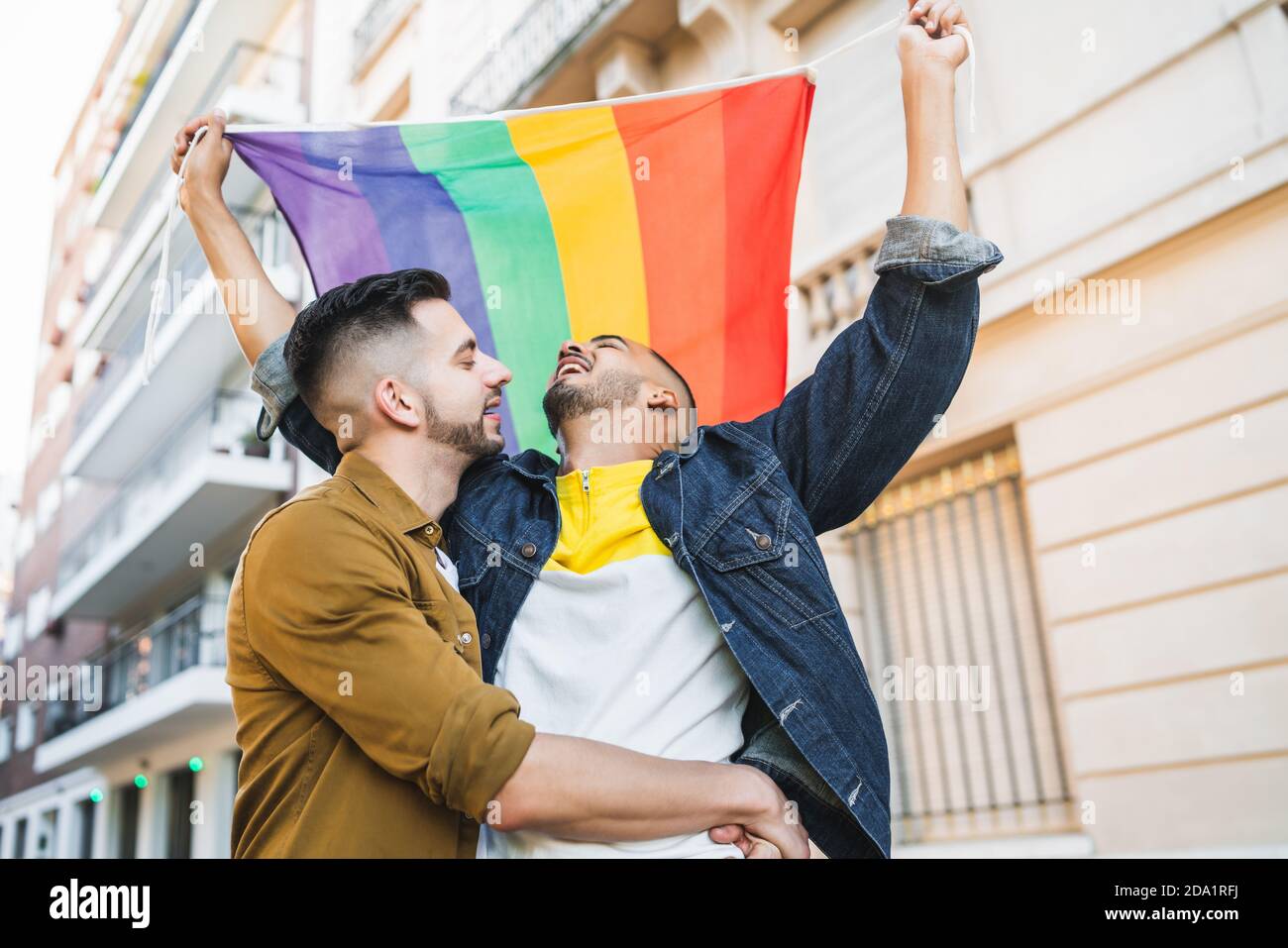 Gay couple embracing and showing their love with rainbow flag Stock ...