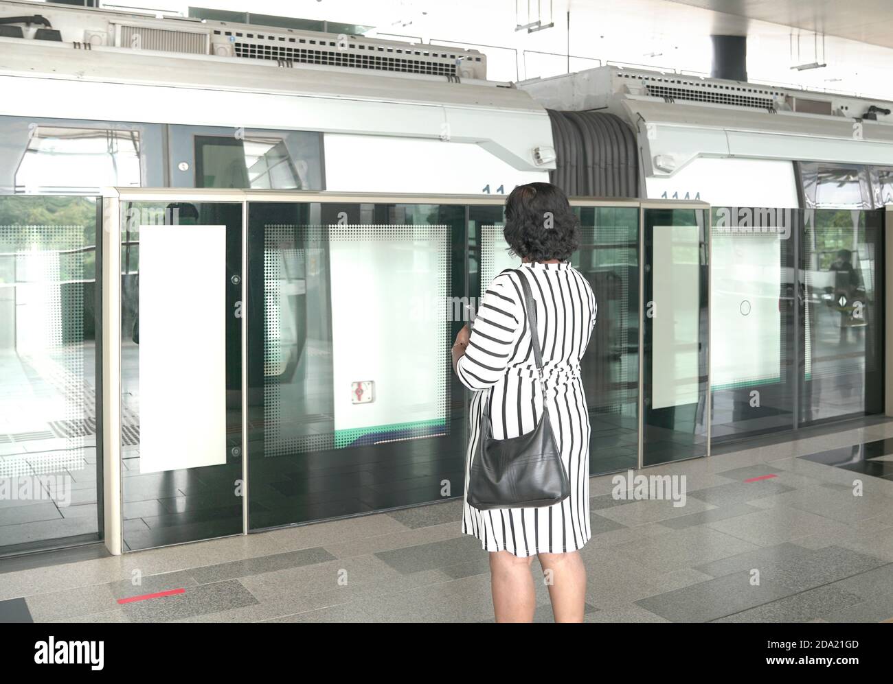 Rear view of woman waiting for train at the platform of a subway ...