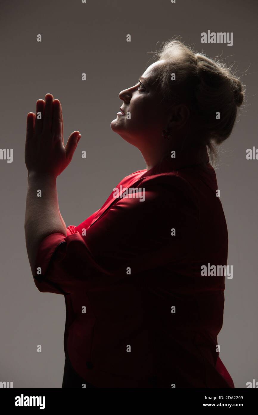 Adult fat woman calls out to God through prayer, hands clasped together ...