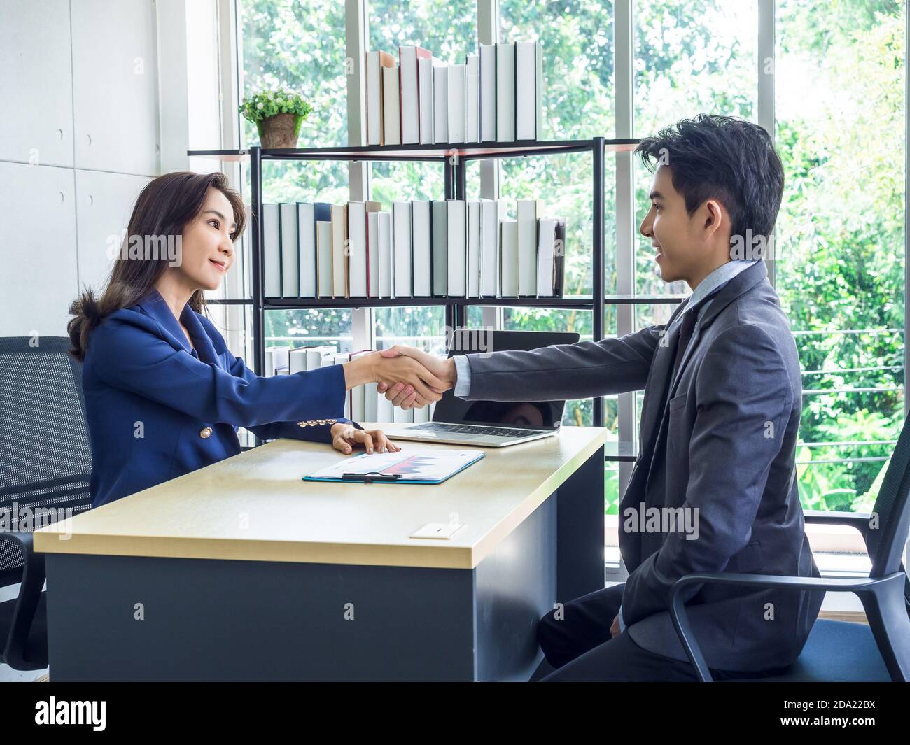 Asian businesswoman and businessman wearing suit shaking hands in ...