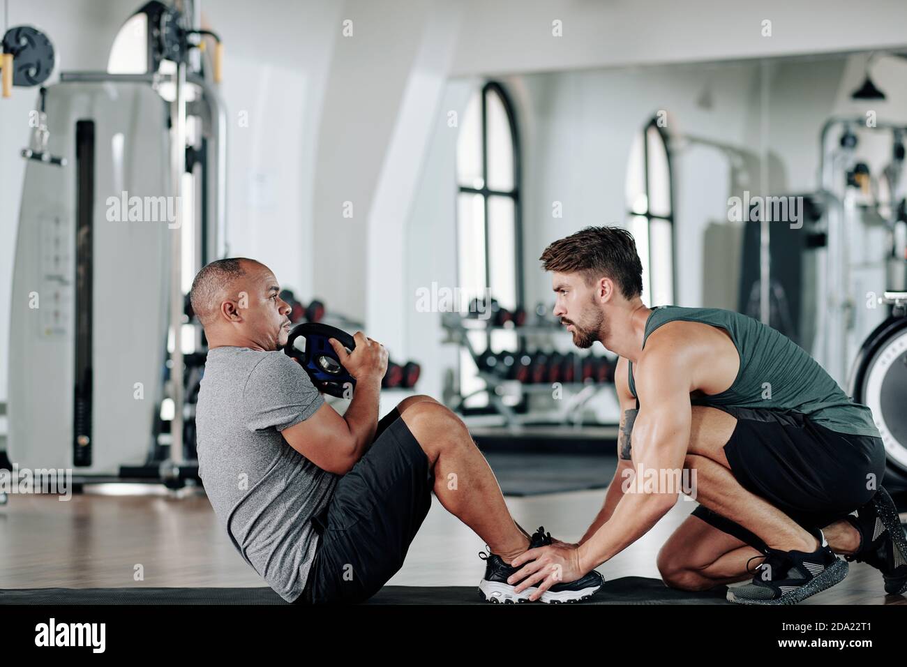 Fitness trainer helping mature client Stock Photo - Alamy
