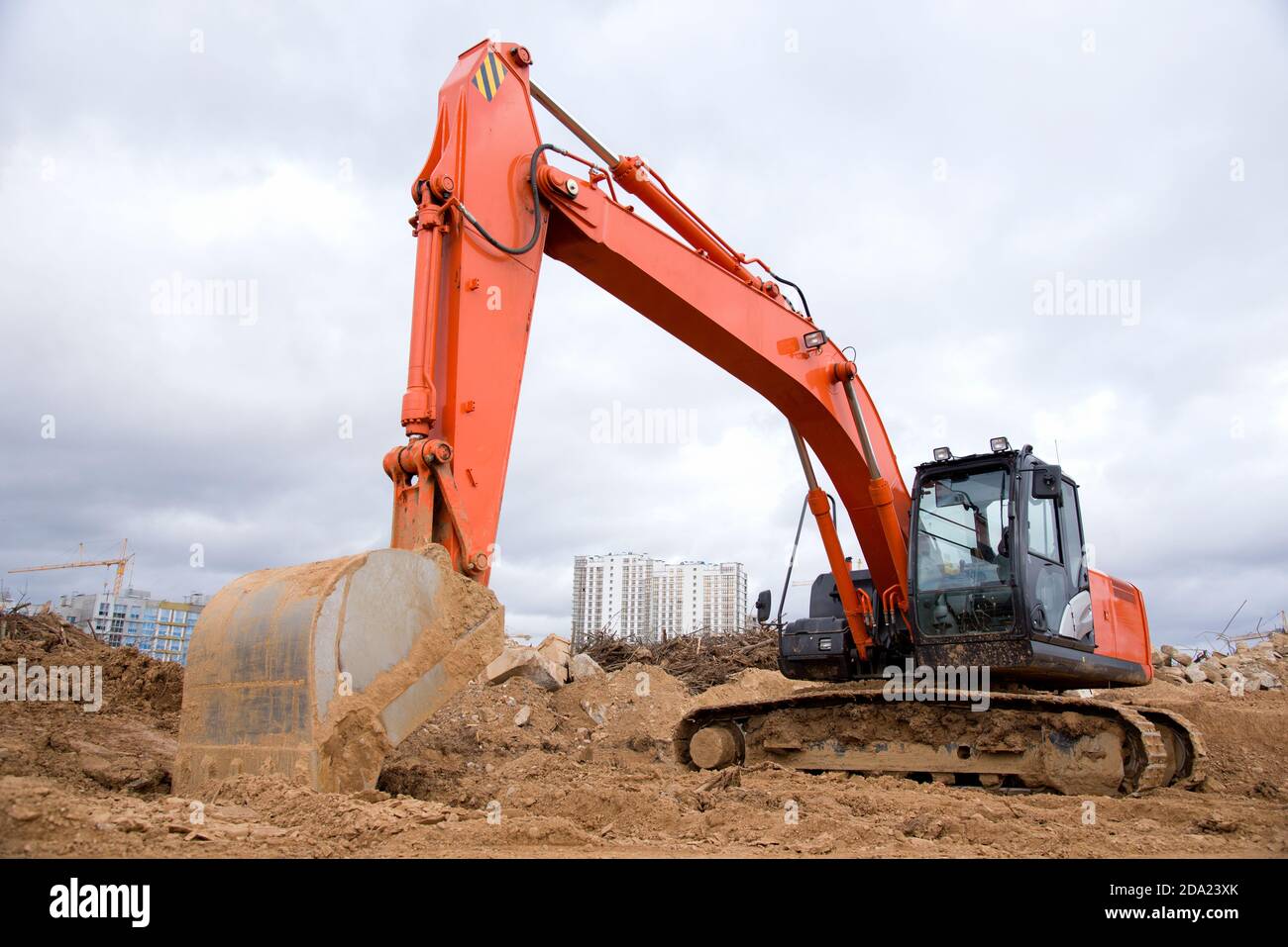 Red excavator during earthworks at construction site. Backhoe digging ...