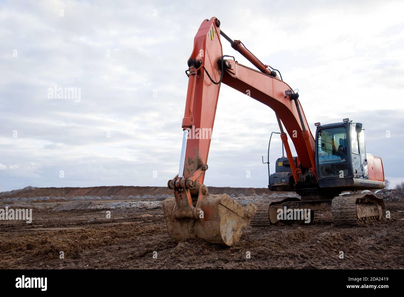 Red excavator during earthworks at construction site. Backhoe digging ...