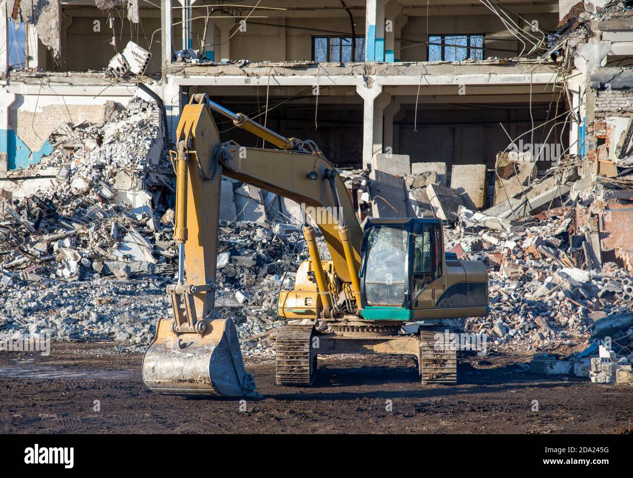 Yellow excavator with bucket at demolition of tall building. Hydraulic ...