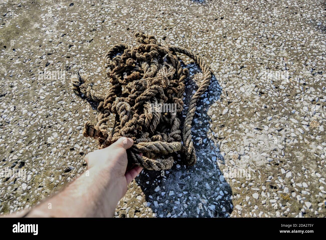 Hand extend to an old and frayed rope standing in a mess. Old rope ...