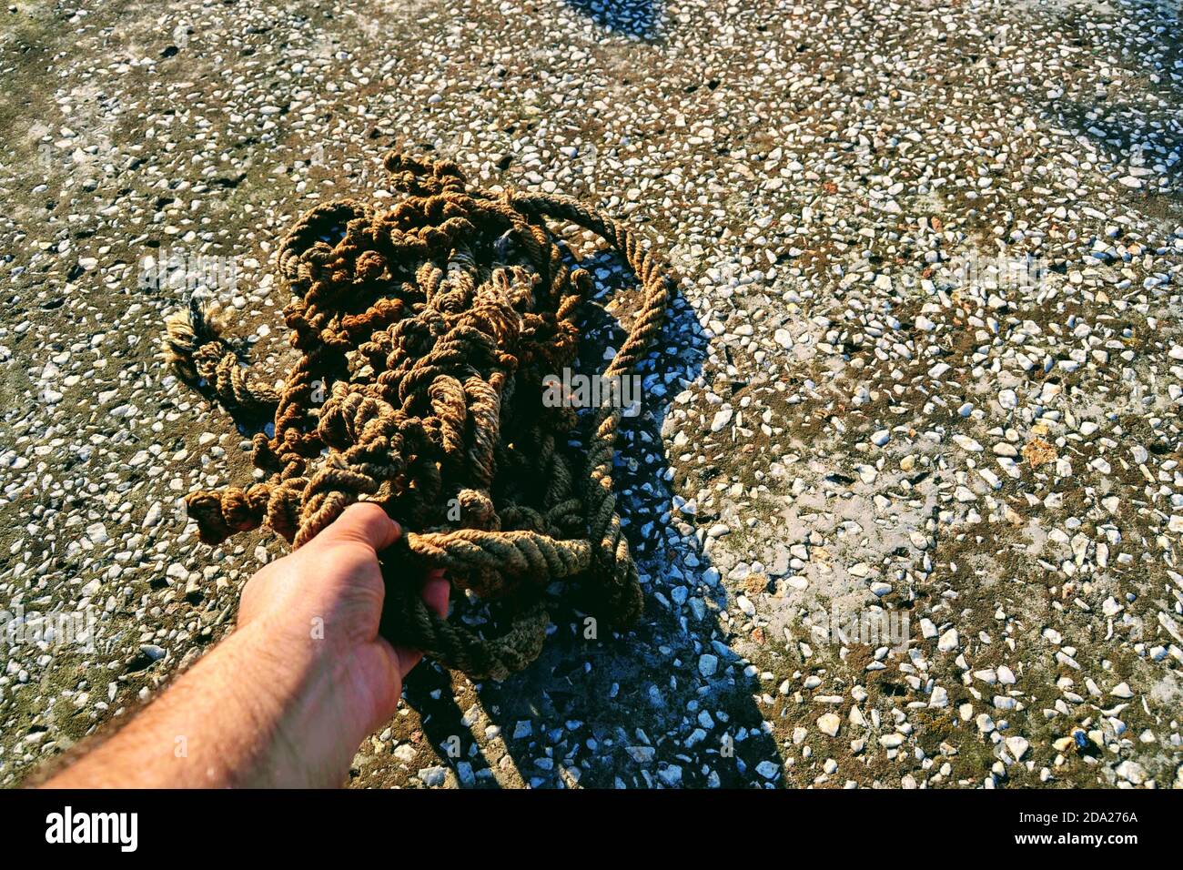 Hand extend to an old and frayed rope standing in a mess. Old rope ...