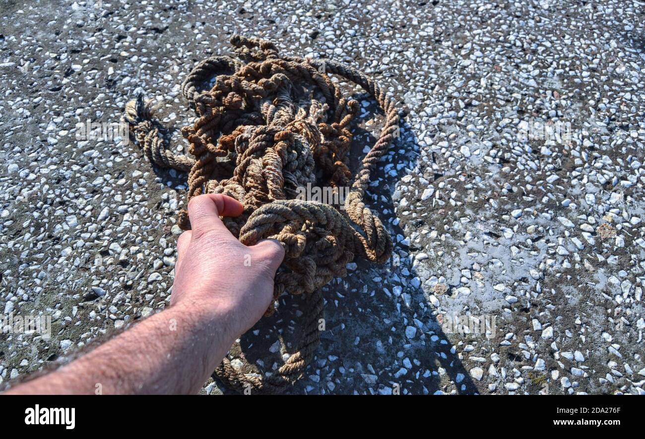 Hand extend to an old and frayed rope standing in a mess. Old rope ...