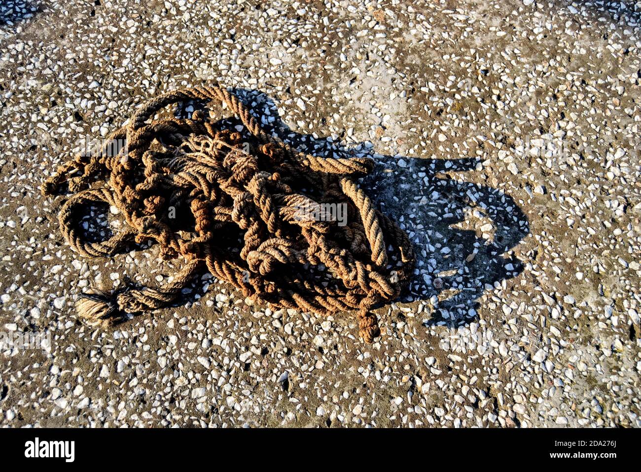 Rope and shadows during sunny day.. An old and frayed rope standing in ...