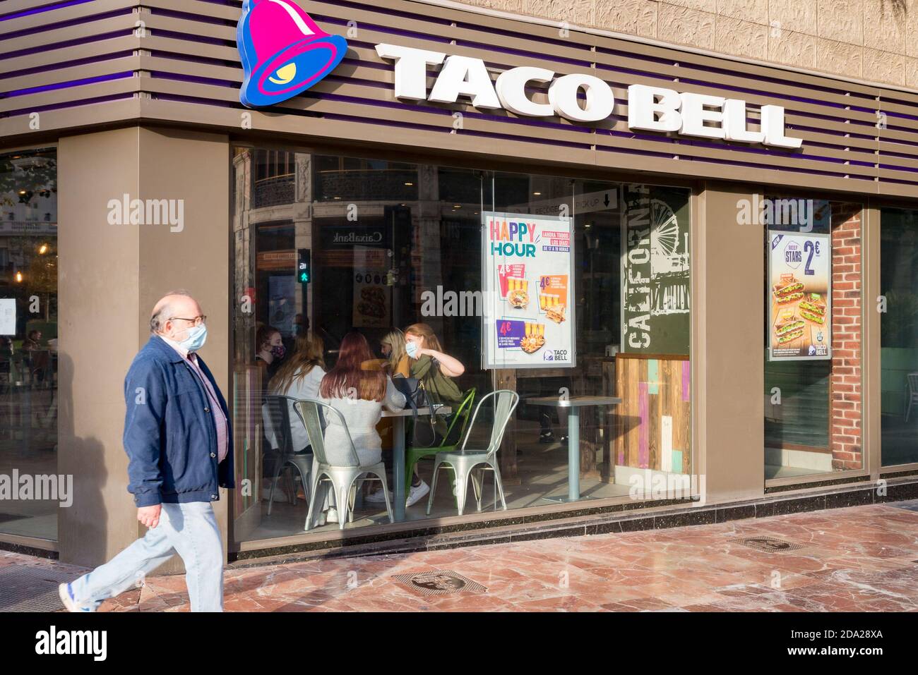 A man wearing a face mask walks past a fast food restaurant Taco Bell ...