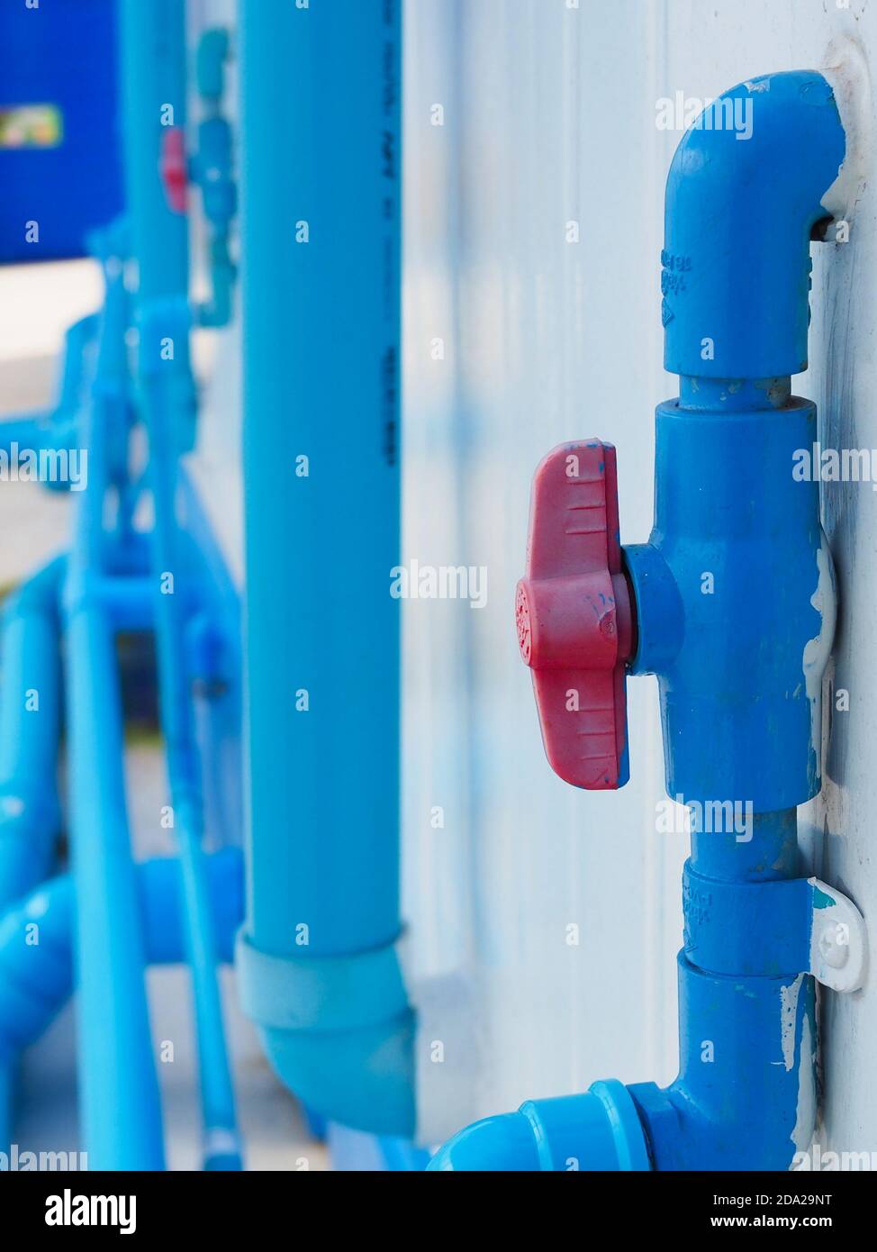 Vertical shot of blue water pipes and red valve Stock Photo - Alamy