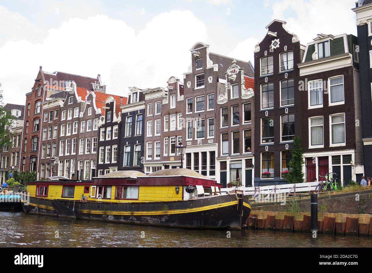 Yellow houseboat and traditional houses - Amsterdam - Netherlands Stock ...