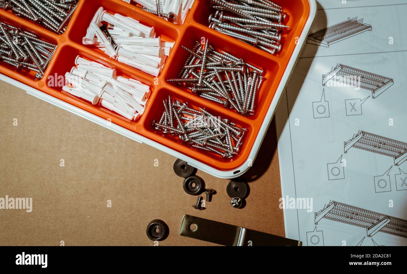 Screws and wall plug in orange plastic box. Top view tool box on brown ...