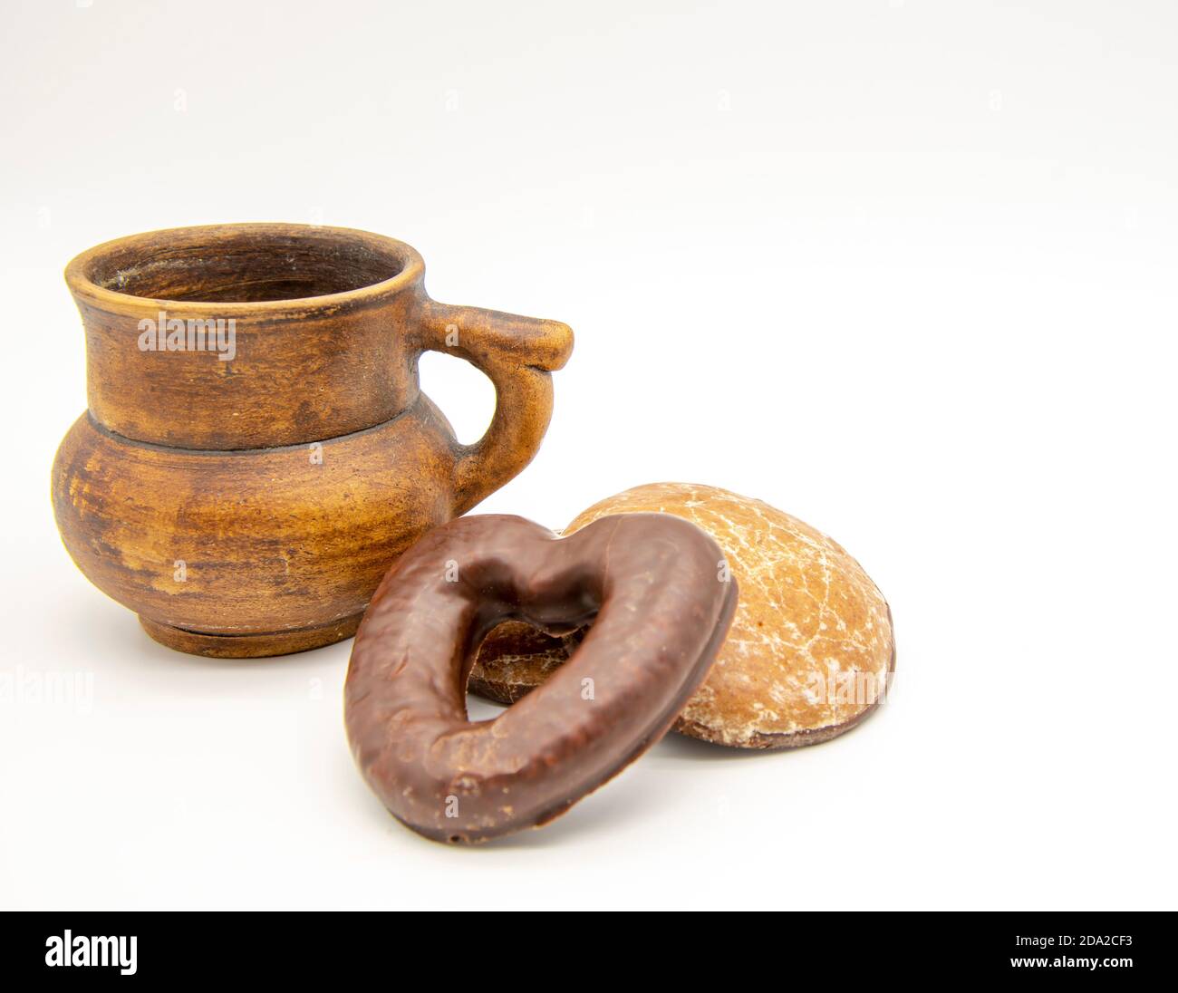 One pottery mug and a few gingerbread cookies on a white background ...