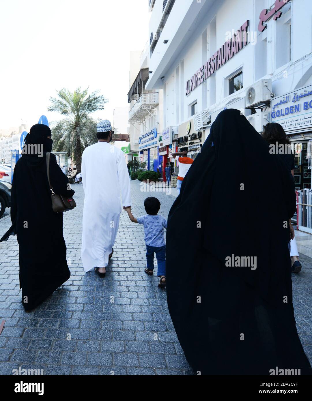 Omani men and women walking on the shopping street by the Mutrah ...