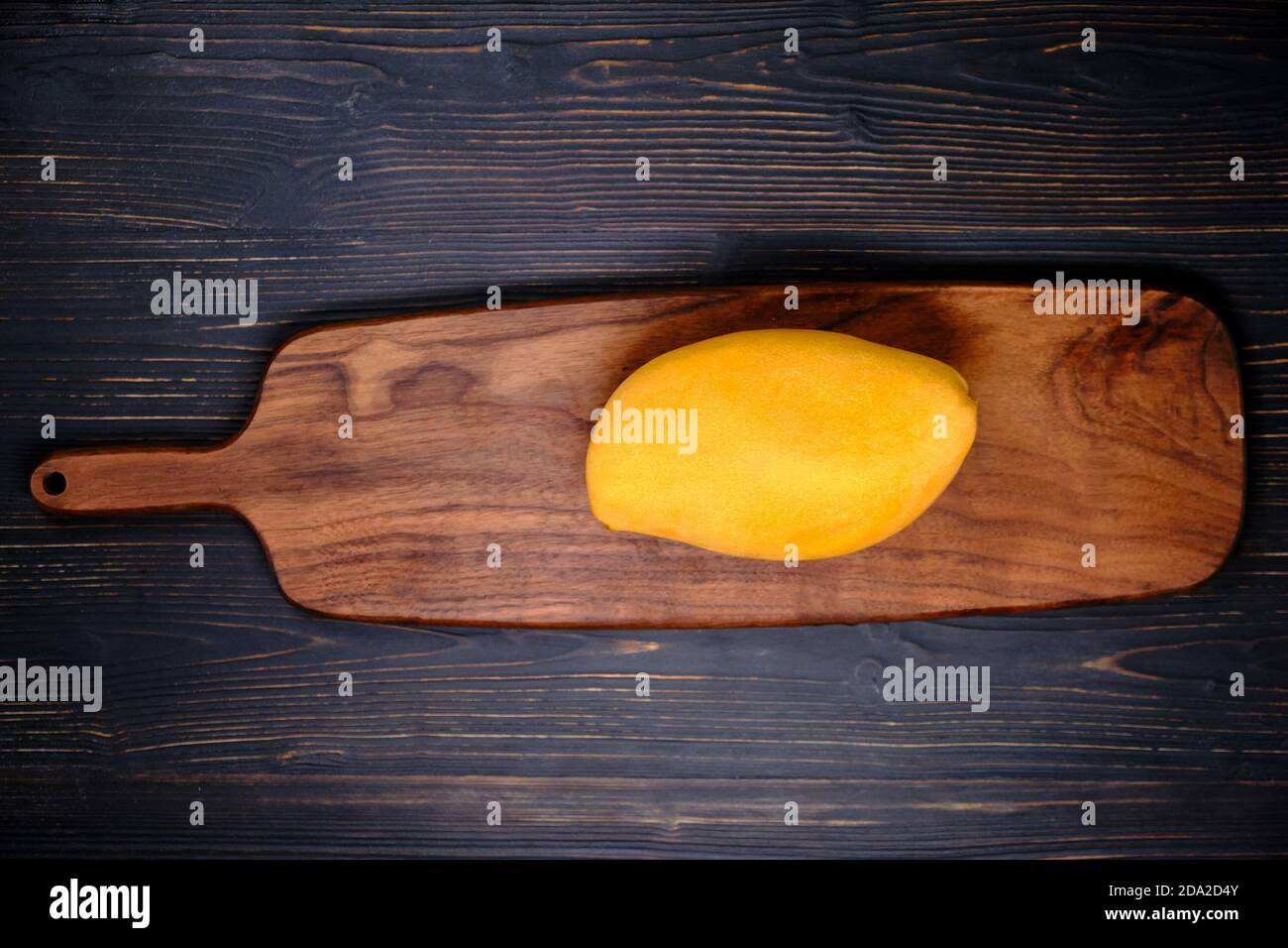 Tropical fruit on kitchen board. Large mango on a wooden table. The big ...