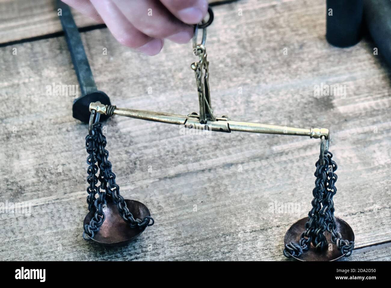 Fingers hold retro scales on a chain. Old scales for weighing gold and ...