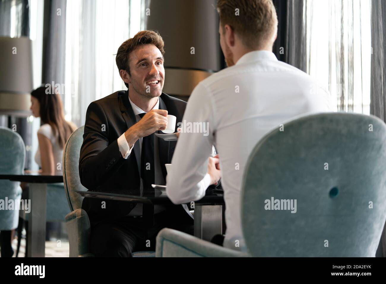 Colleagues and friends. Two cheerful businessmen drinking coffee and ...