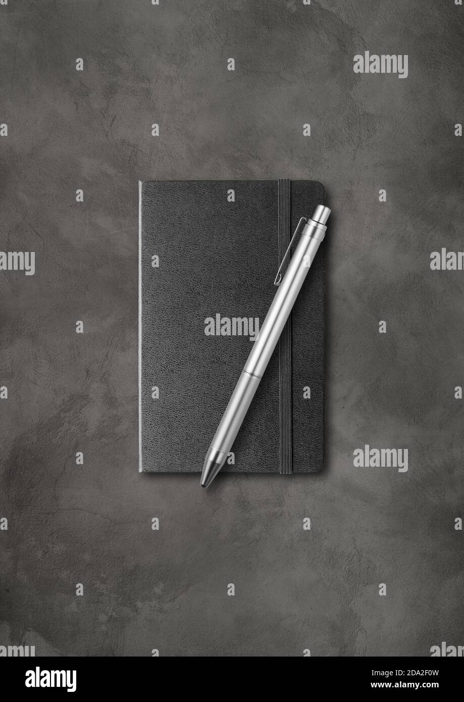 Black closed notebook with a pen. Mockup isolated on dark concrete ...