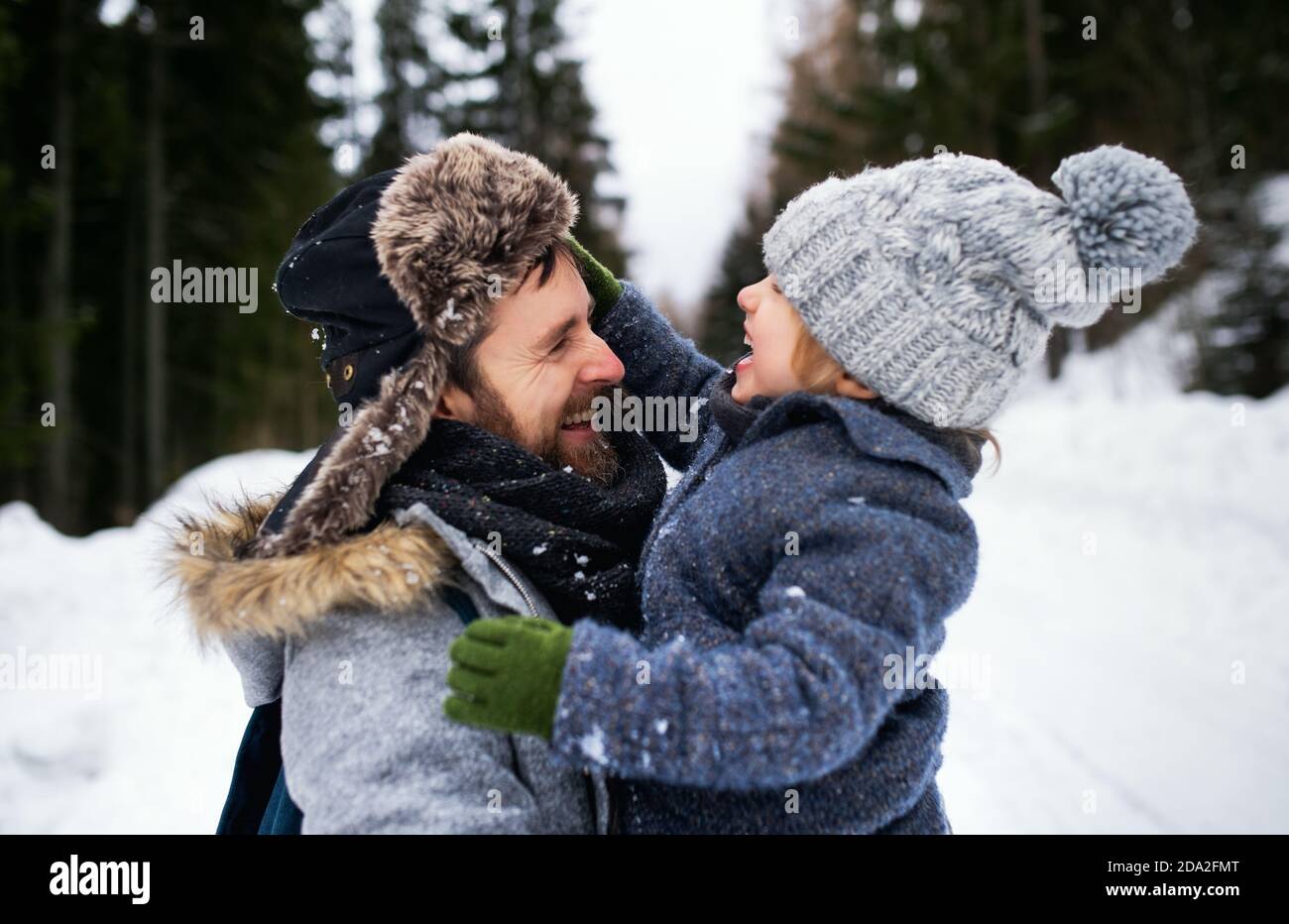 Side view of father with small son in snowy winter nature, talking and ...