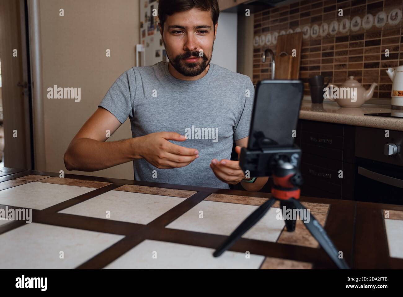 Young man having video call via smartphone in the home office. Virtual ...