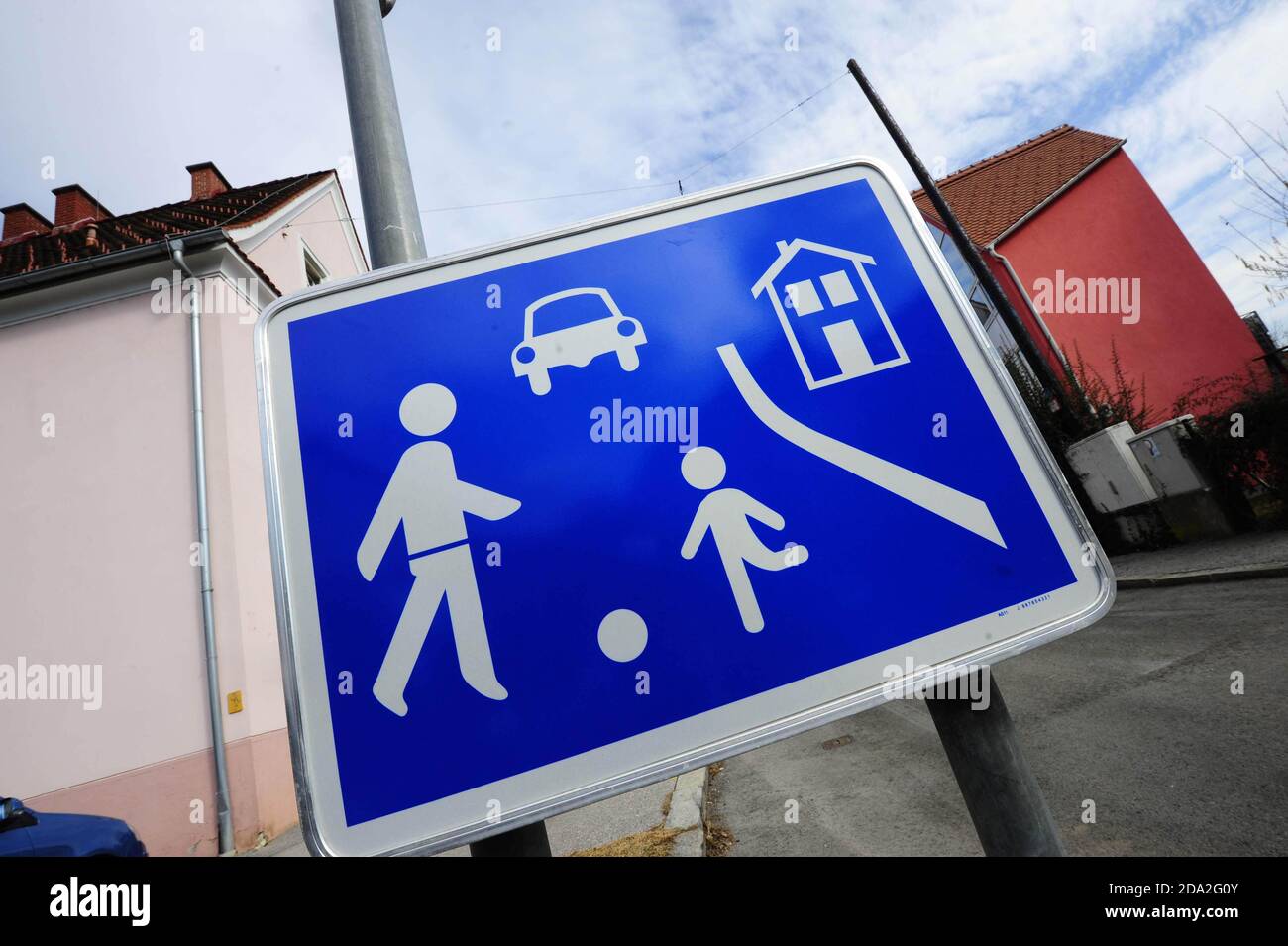 blue residential street sign, drive slow, street and houses in the back ...