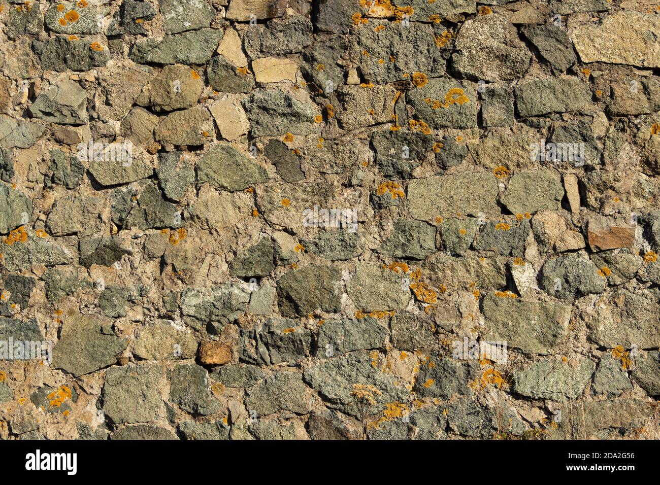 The surface of an old stone wall, masonry of uneven wild hewn stones ...