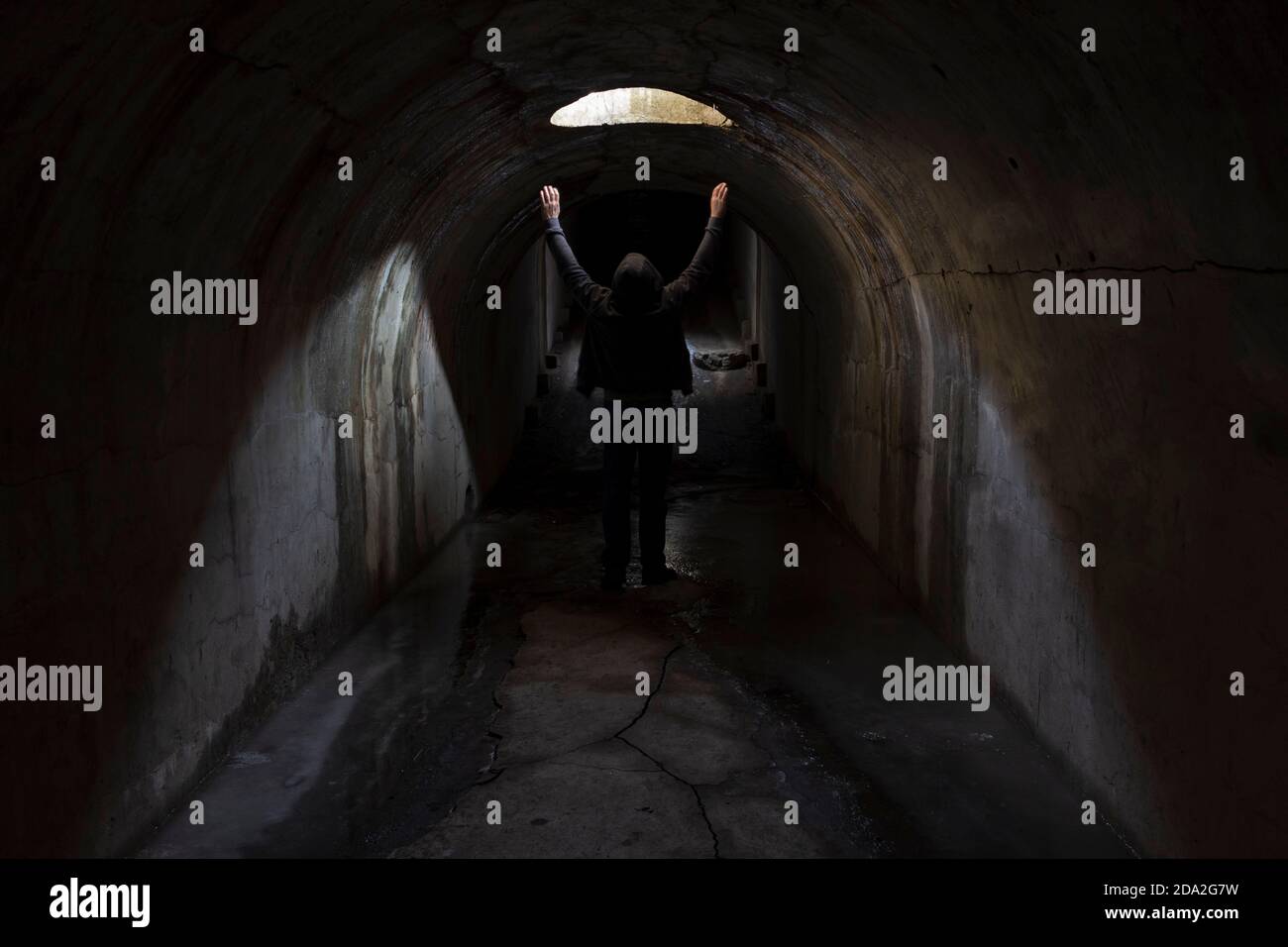 A man in a dark underground tunnel is looking for a way out and raises ...