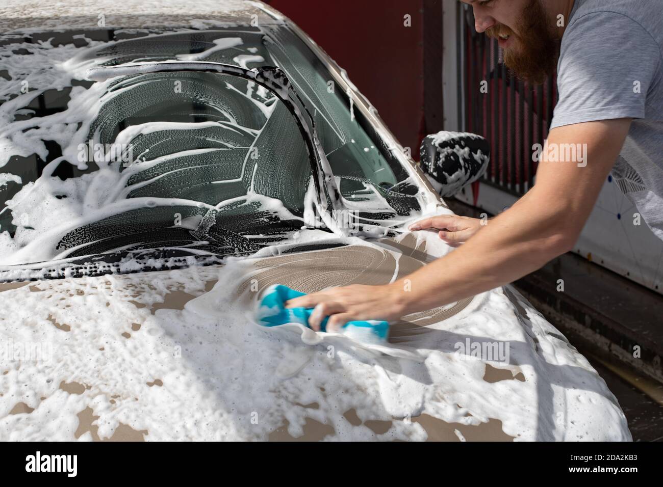 Male motorist washing car with a washcloth and shampoo, auto covered ...
