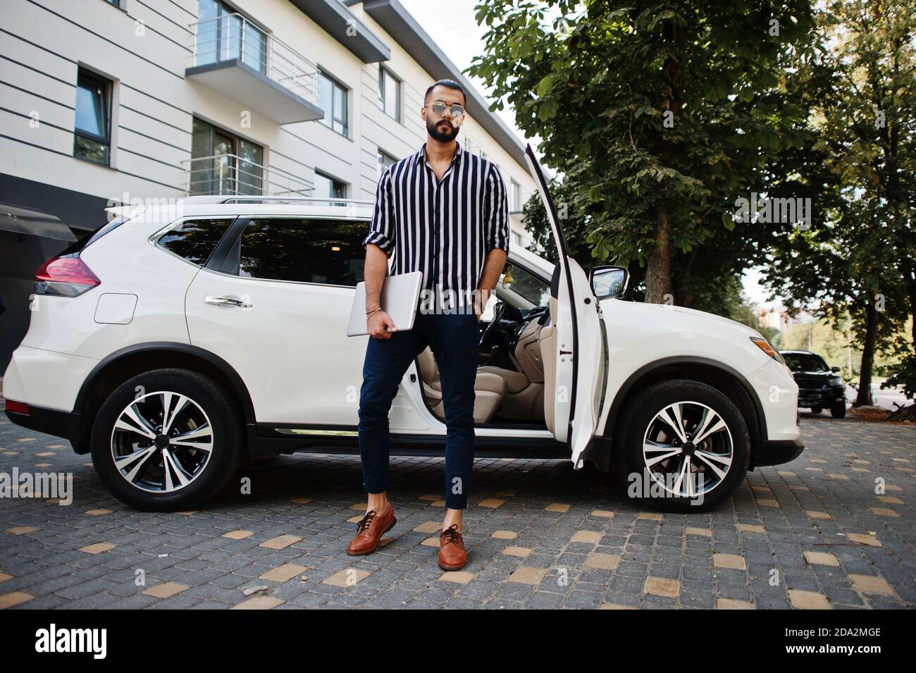 Successful arab man wear in striped shirt and sunglasses pose near his ...