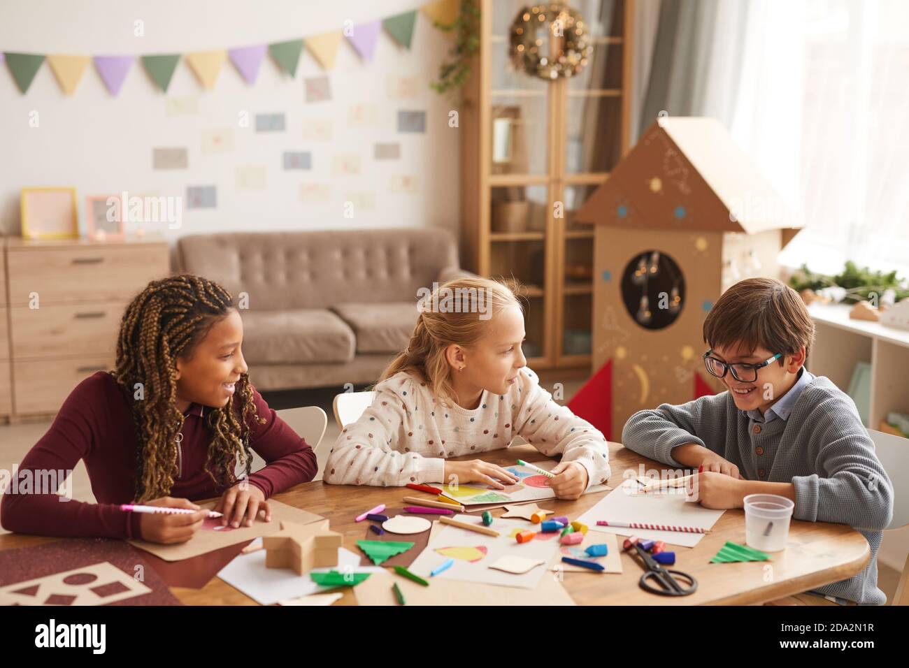Multi-ethnic group of children drawing pictures together while enjoying ...